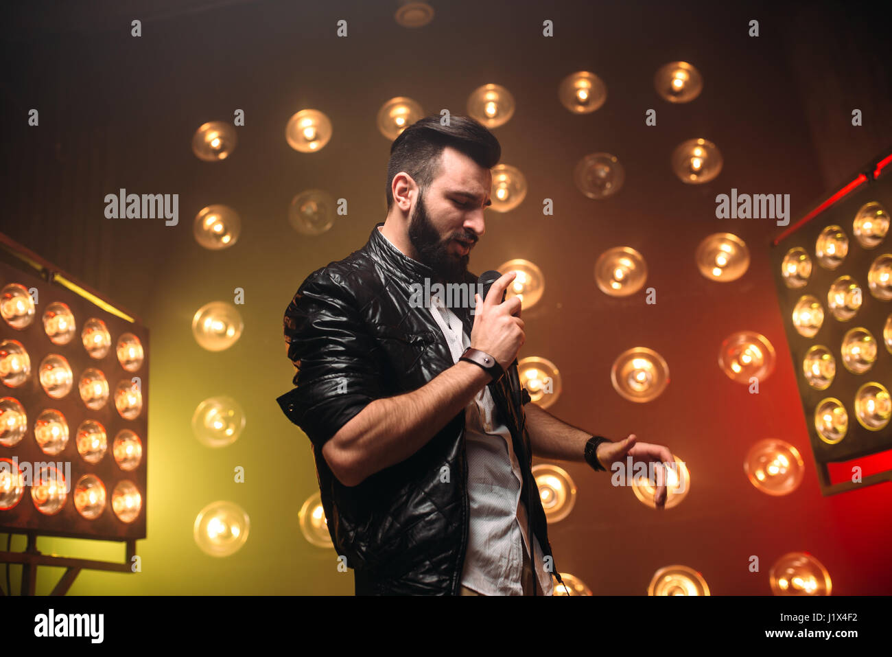 Brutal bearded singer with microphone sing a song on the stage with the ...