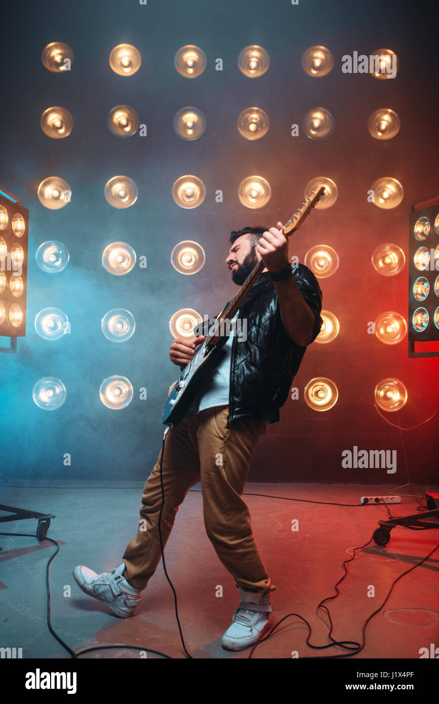 Male solo musican with electro guitar on the stage with the decorations ...