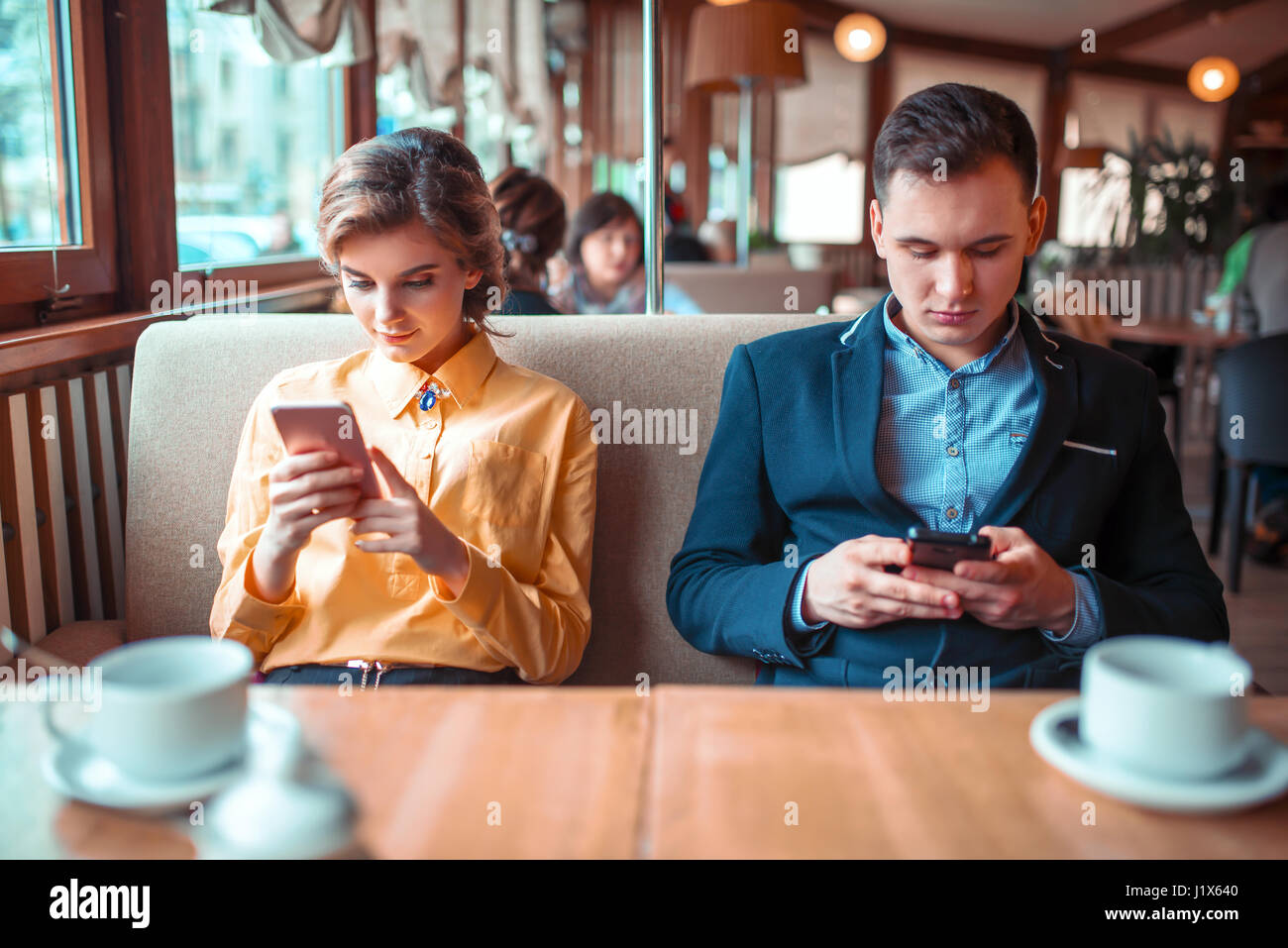 Love couple use their mobile phones in restaurant. Man and woman on ...