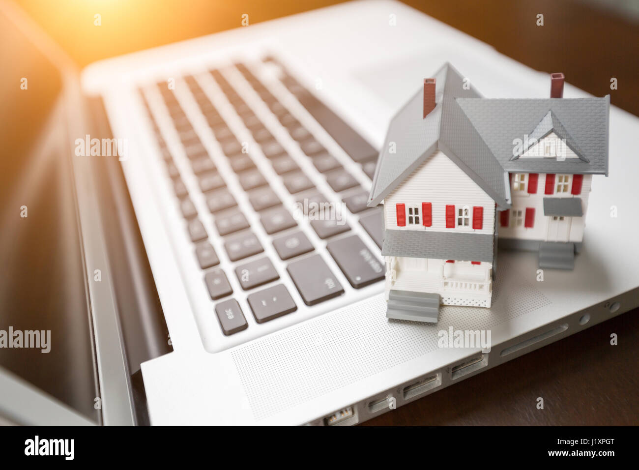 Miniature House And Laptop Computer Resting on Desktop Stock Photo - Alamy