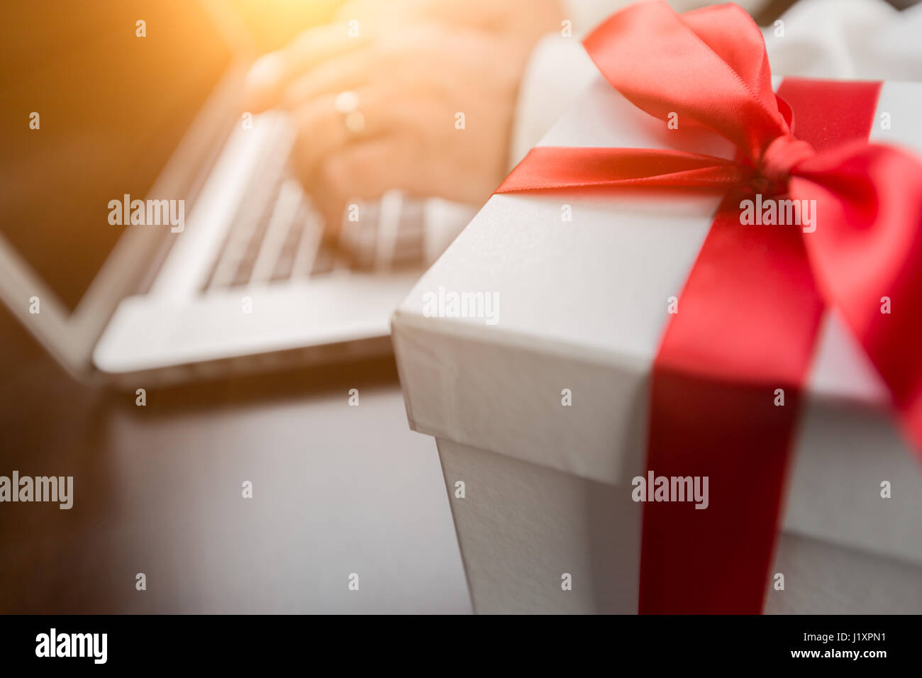 White Gift Box with Red Ribbon and Bow Near Man Typing on Laptop ...