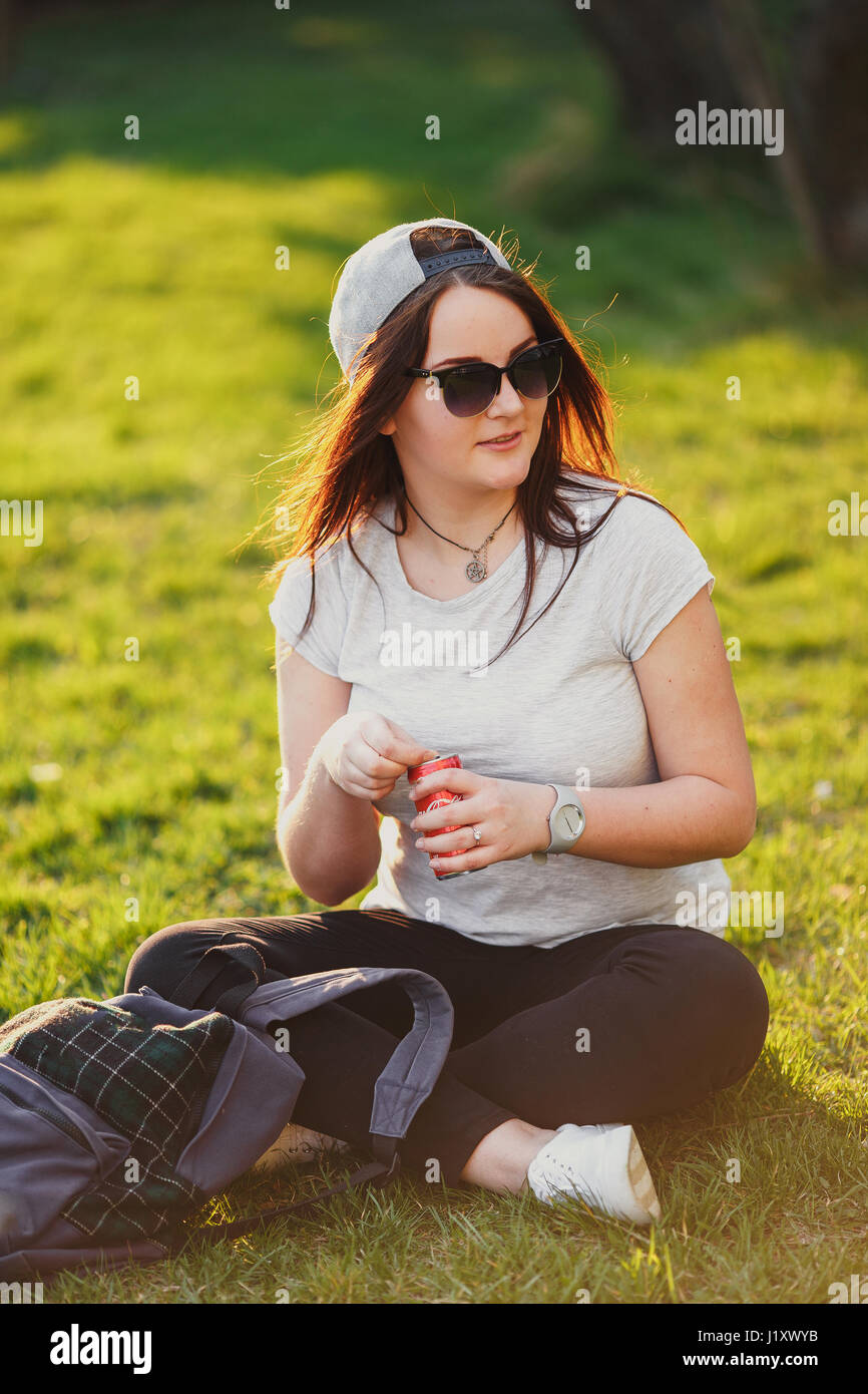 Pretty girl drink coda at park background with sunset Stock Photo - Alamy