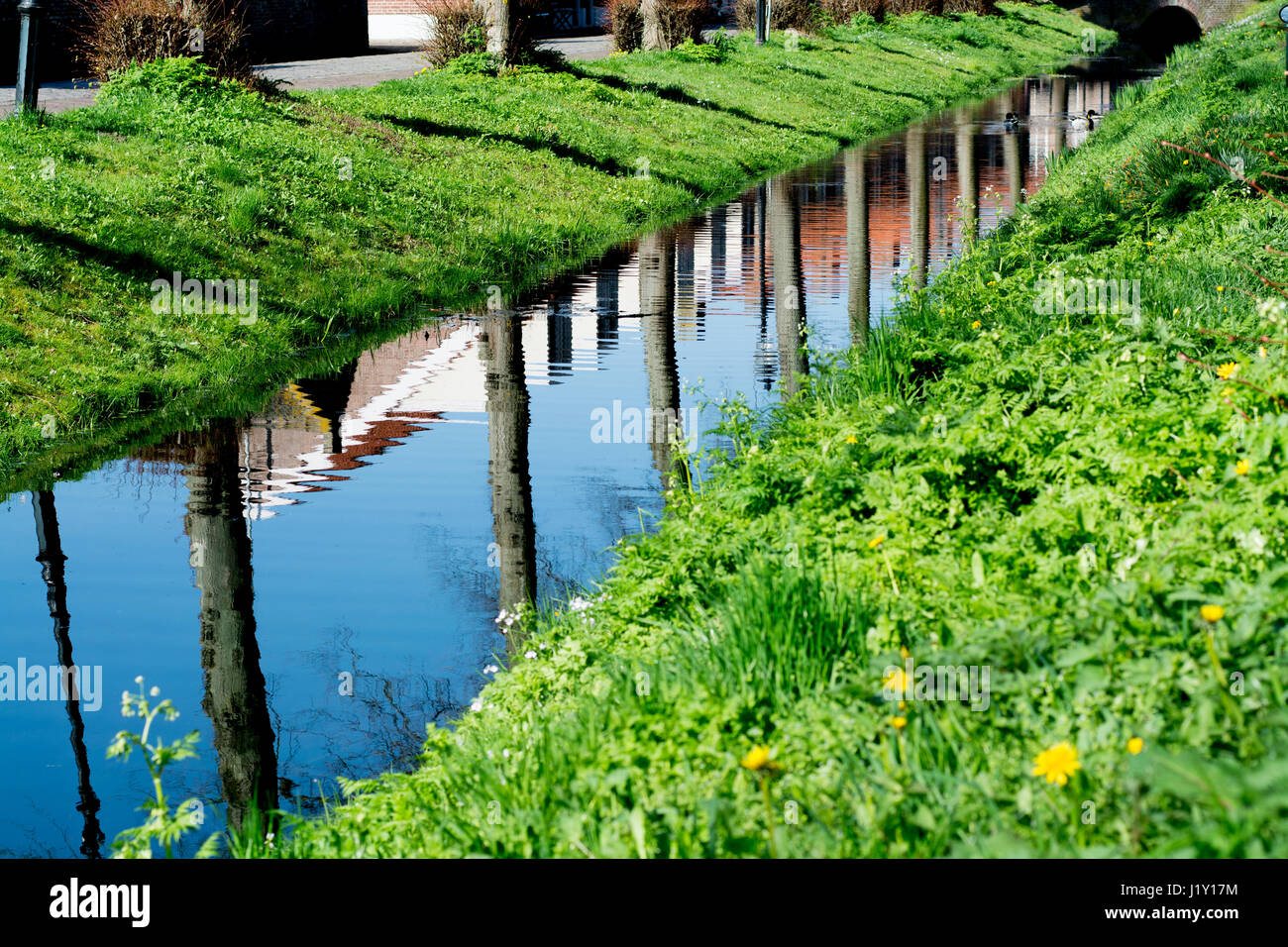 Walking along the small canal in old Dutch village Heusden, sunny ...