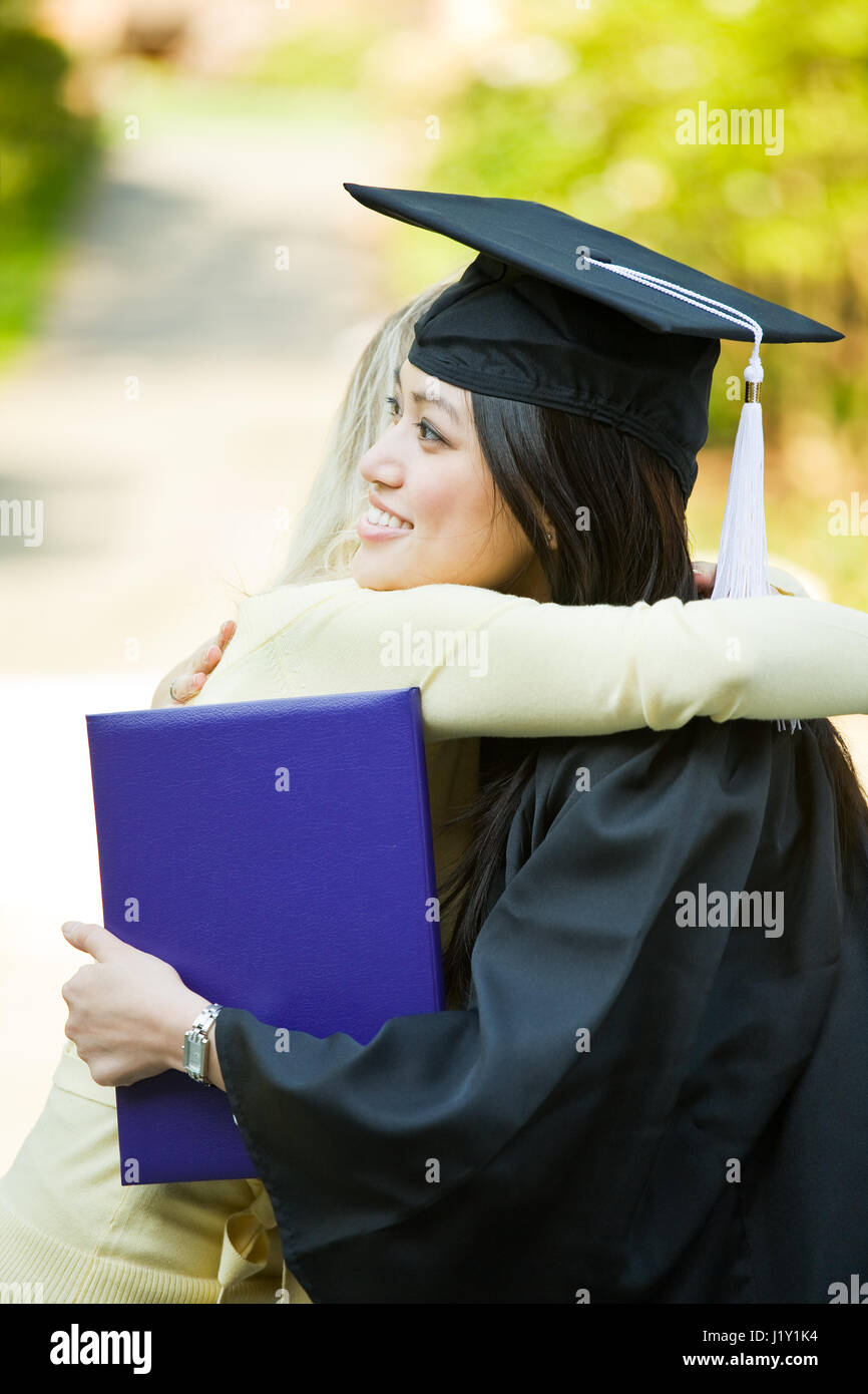 A happy beautiful graduation girl being congratulated by her friend ...