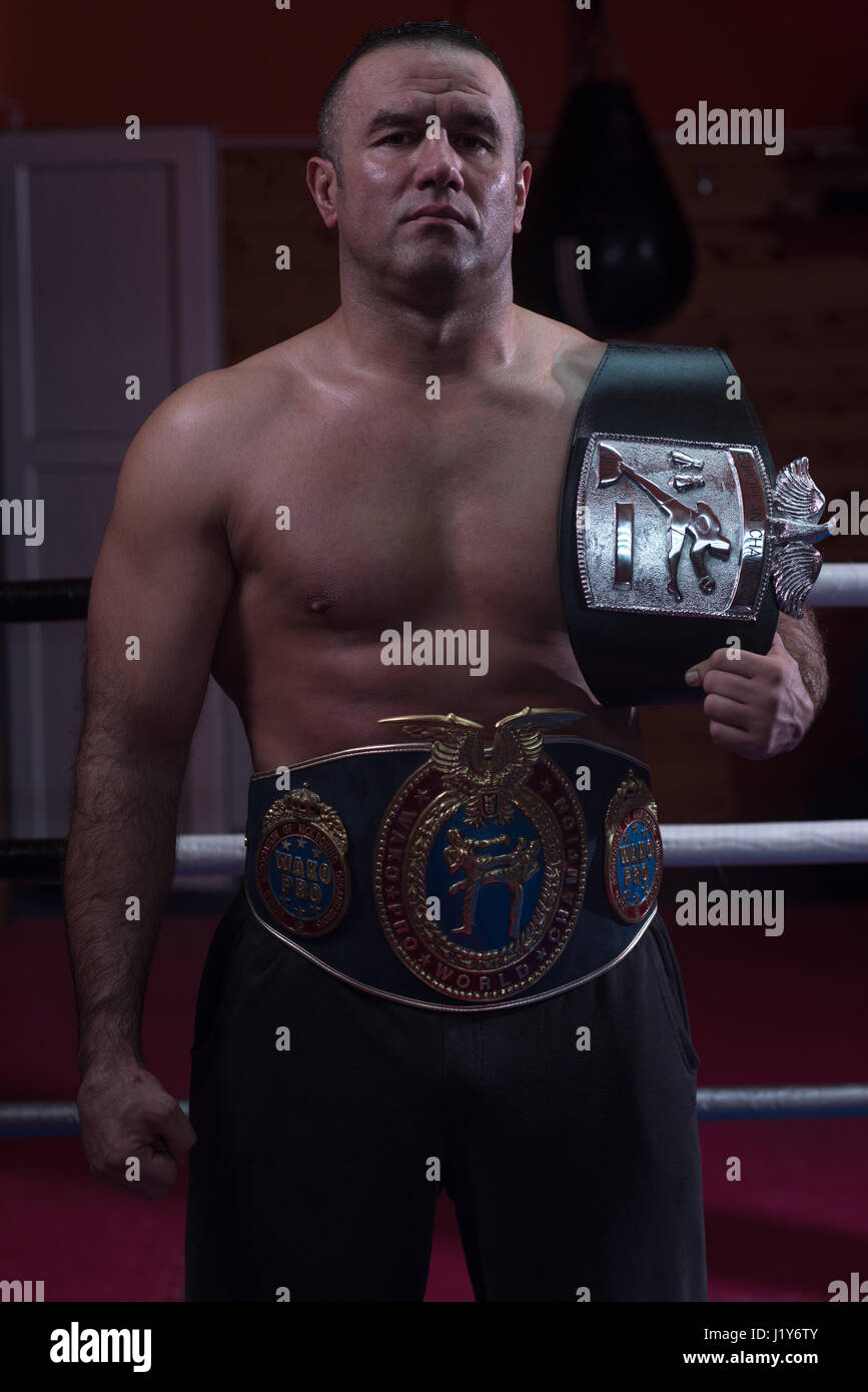 portrait of muscular professional kick boxer with his championship belt ...