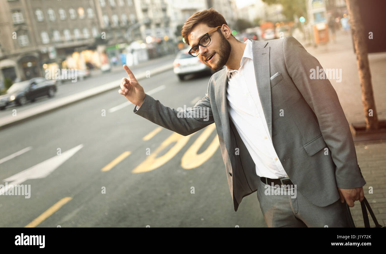 Businessman waving for a taxi in busy city Stock Photo - Alamy
