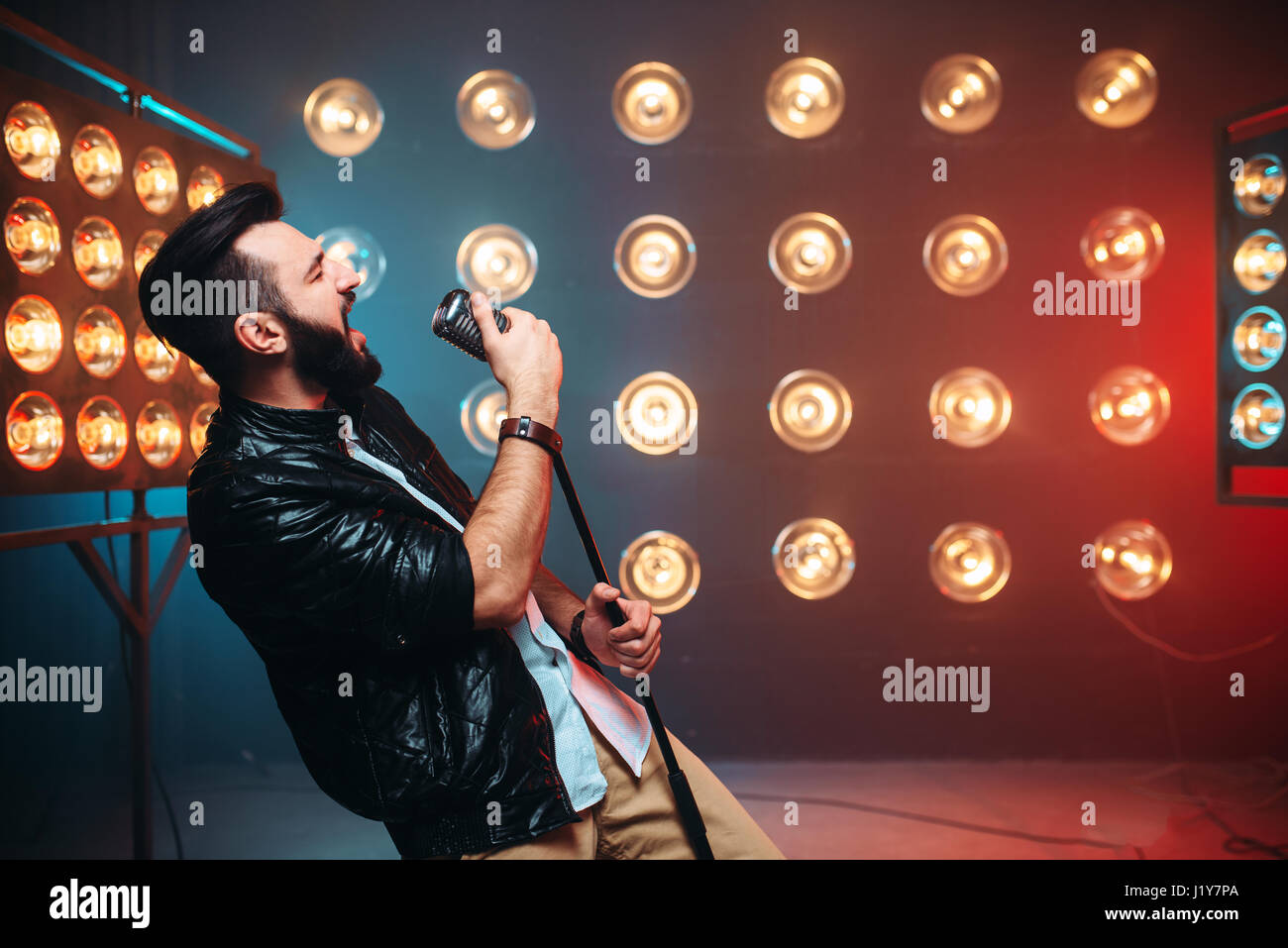 Brutal bearded singer with microphone on the stage with the decorations ...