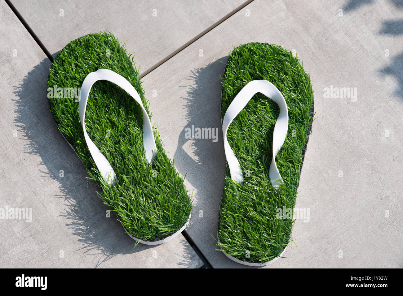 Flip flops with green grass sole stand in the sun Stock Photo - Alamy