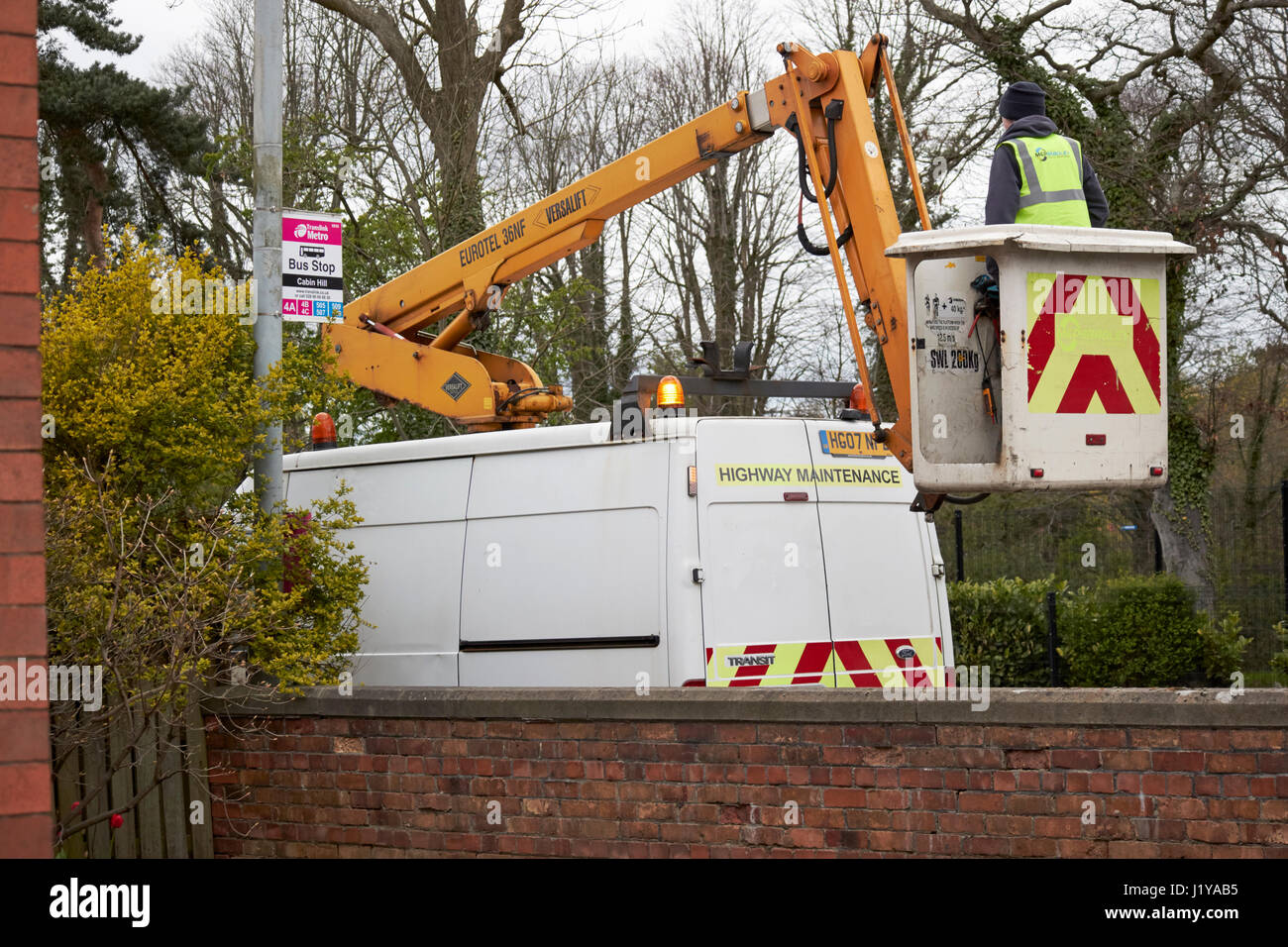 man operating elevated platform attached to a van to repair street ...