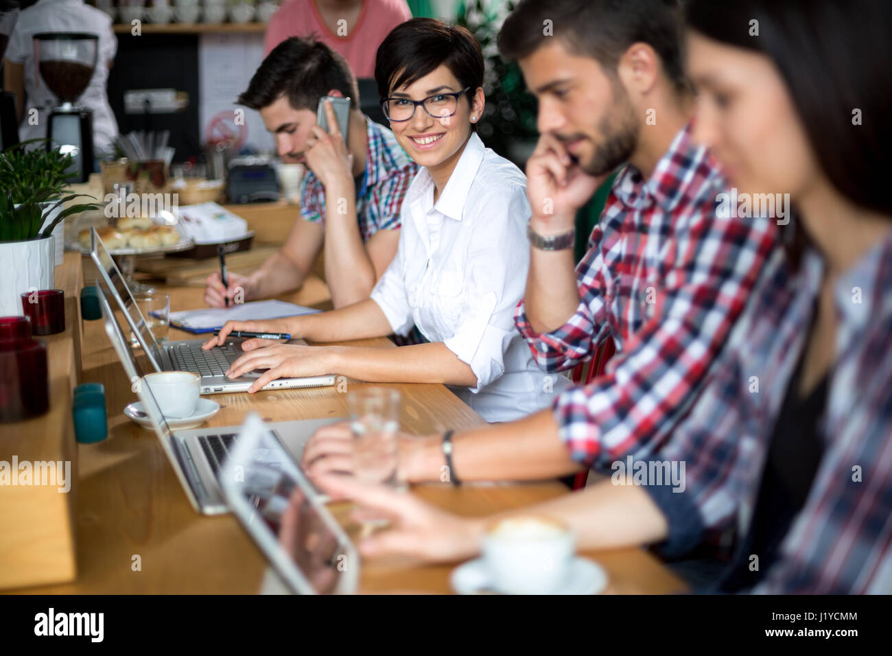 Three students studying and learning in a coffee shop with a laptop and ...