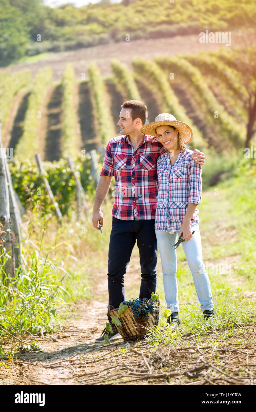 Love in vineyard, young romantic couple standing between rows of vines ...
