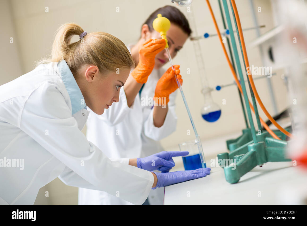 Two female assistant in lab take liquid with big pipette Stock Photo ...