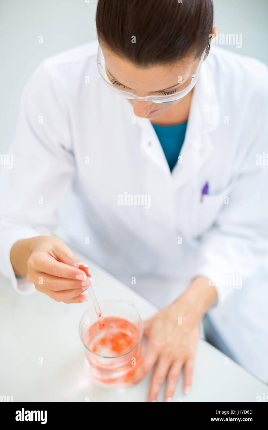 Laboratory technician take liquid from glassware with glass pipette ...
