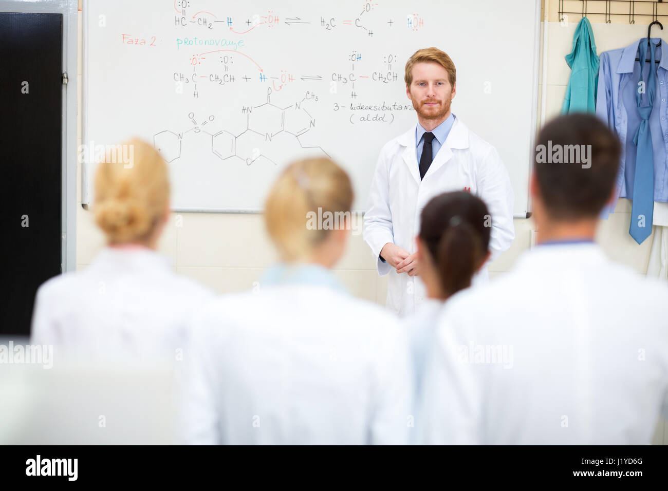 Young university professor studying students in front of blackboard ...