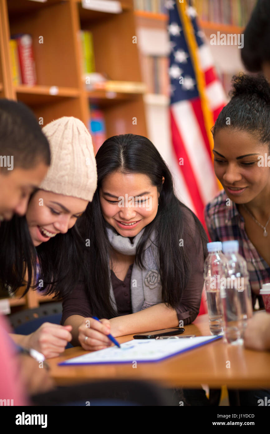 Classmates having fun and studying together for lecture in library ...