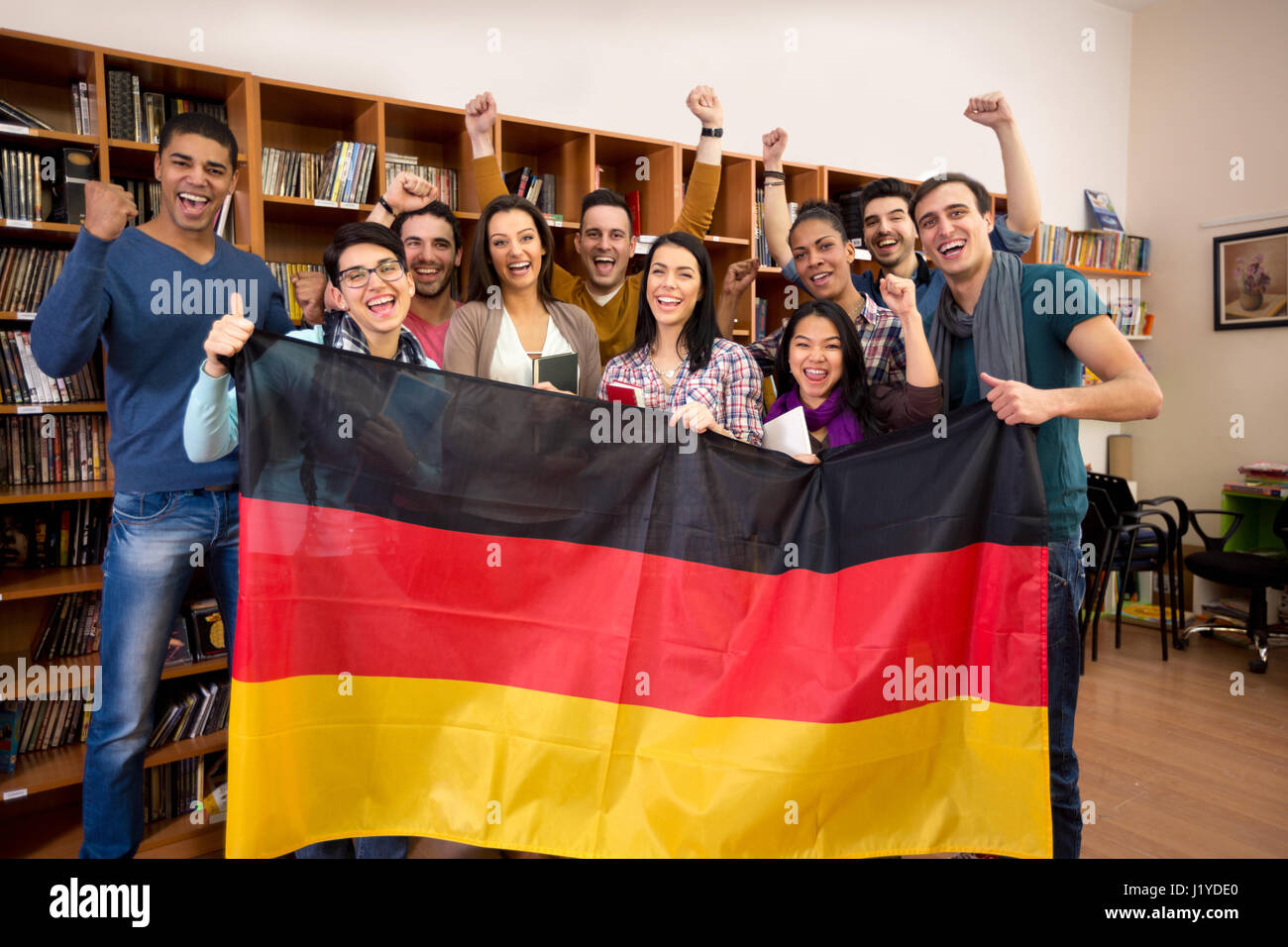 Excited students with hands raised and smiling faces present Germany ...