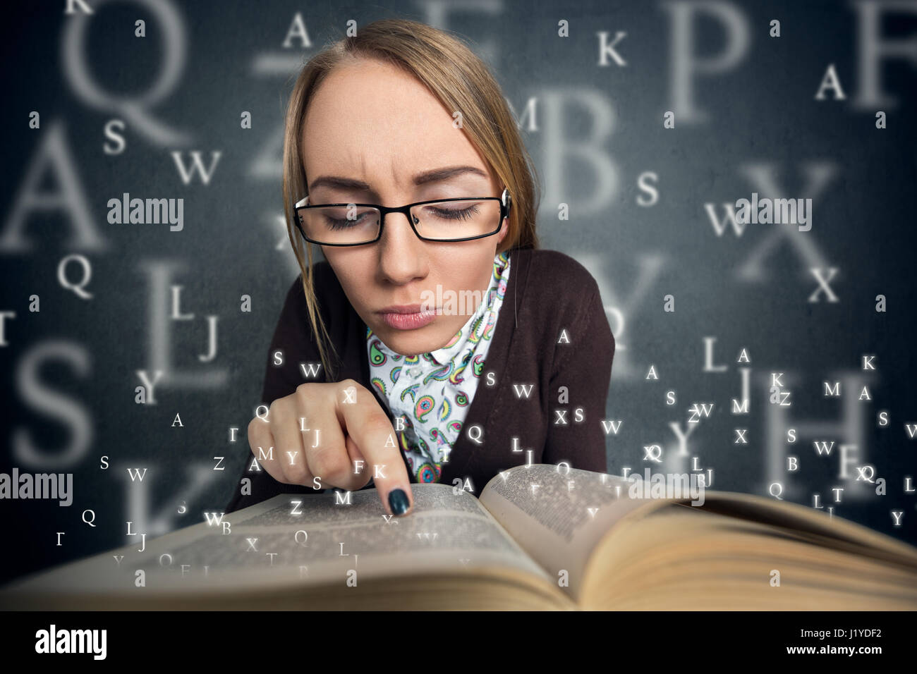 Young girl reading a book with alphabet letters coming out of the book ...