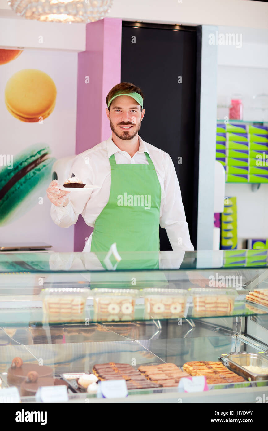 Worker in pastry shop holding cake plate with cupcake Stock Photo - Alamy