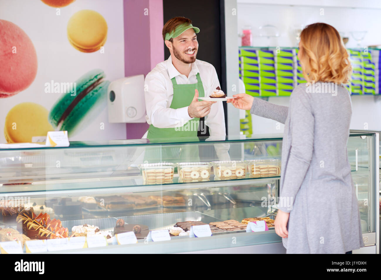 Seller men in confectionery gives cup cake to female customer Stock ...