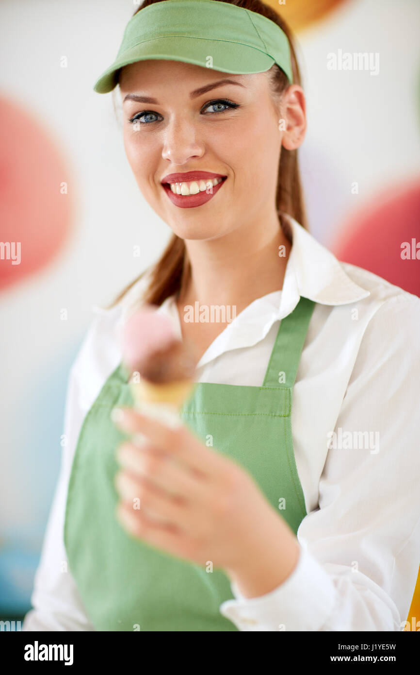 Young attractive woman employed in candy store with ice cream in cone ...