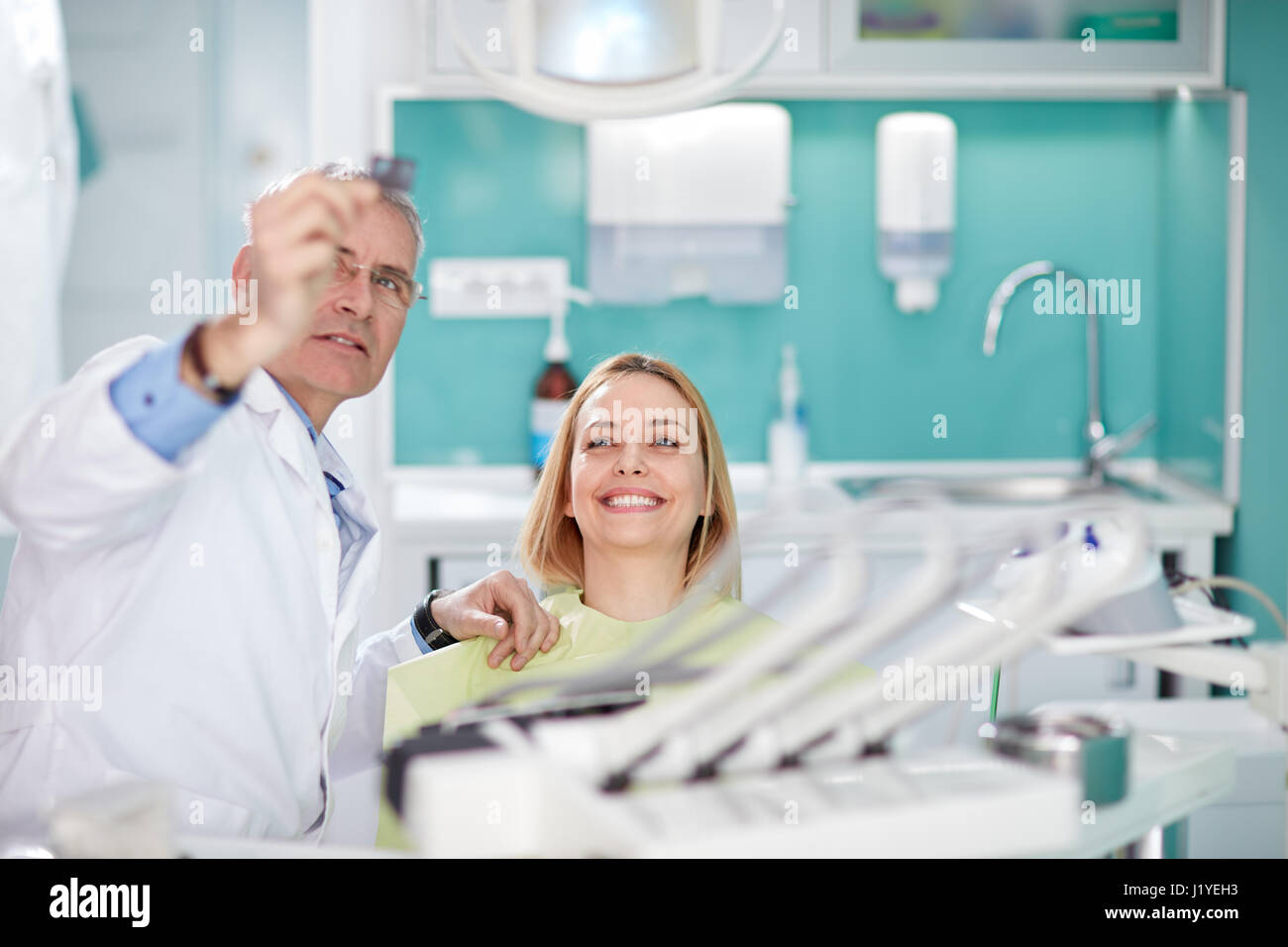 Smiling female woman in dental chair with dentist looking at dental ...