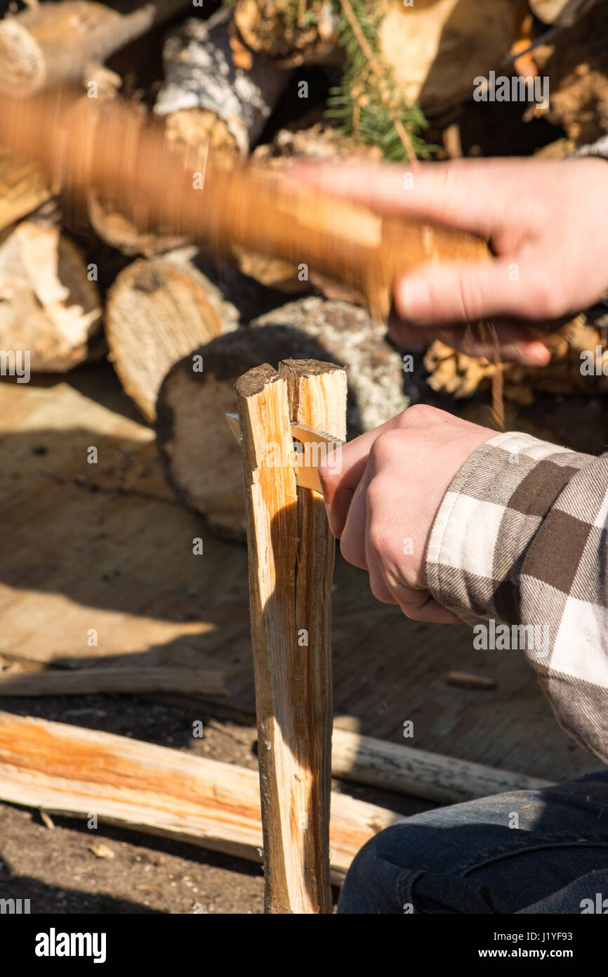 male splitting wood primitively with small log and hunting knife Stock ...