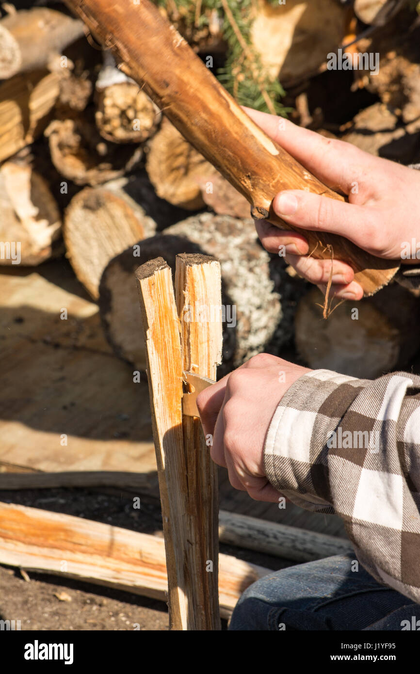 male splitting wood primitively with small log and hunting knife Stock ...