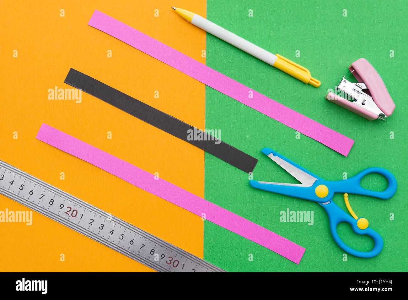 ruler scissors stapler and hand cut paper straps on colorful scrapbook ...