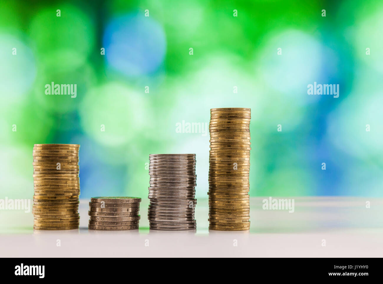 Growing coins stacks with green and blue sparkling bokeh background. Financial growth, saving ...