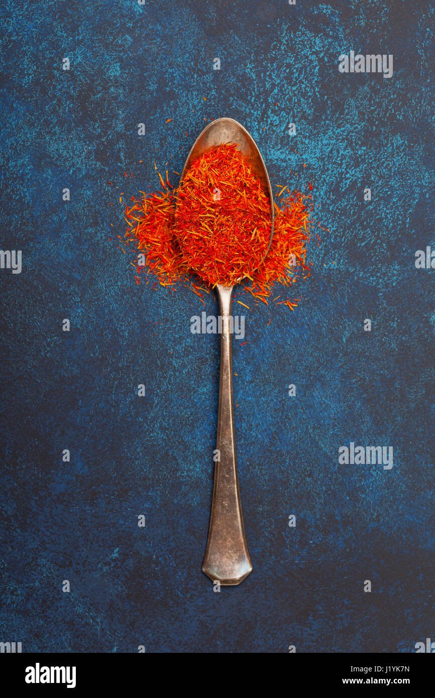 Saffron in an old silver spoon on a blue background. View from above ...
