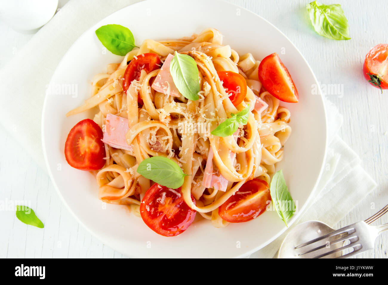 Tagliatelle pasta with ham, tomato sauce, cherry tomatoes and basil ...