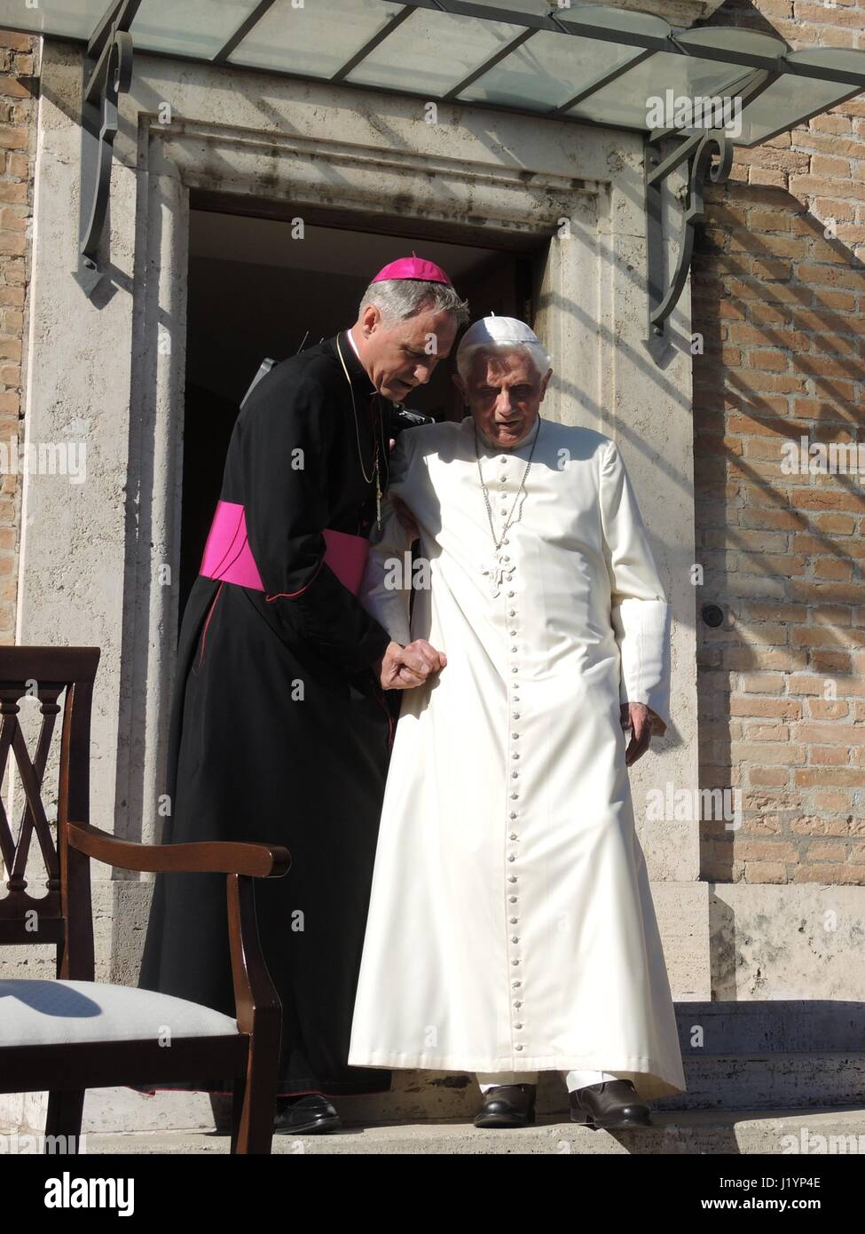 Pope Emeritus Benedict XVI (R), born Joseph Ratzinger, is assisted by ...