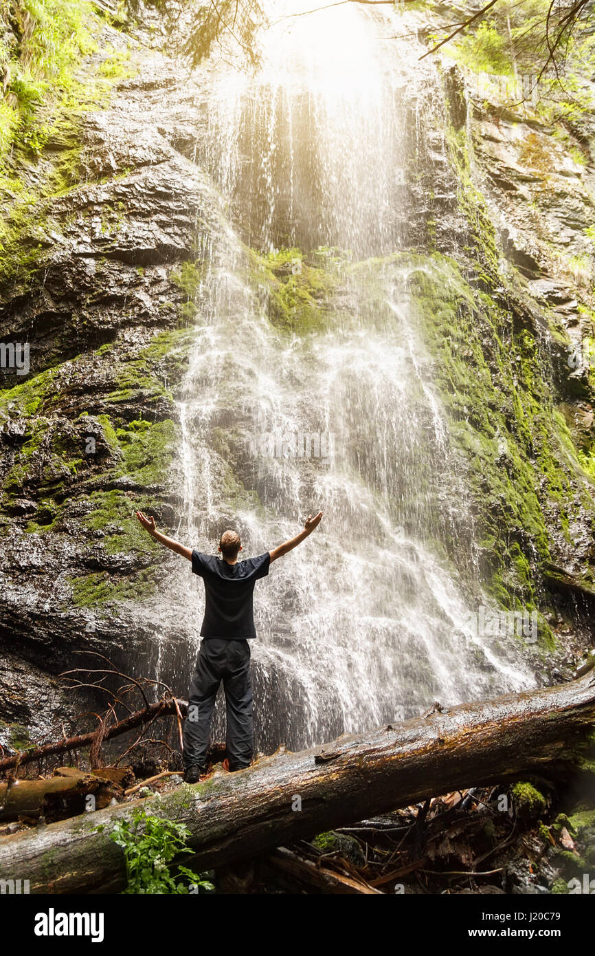 man embracing waterfall with open arms. Tourist looking at the ...