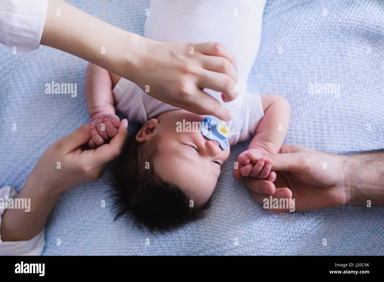 Parents with Newborn Baby Boy. Hand corrects the pacifier to the child ...