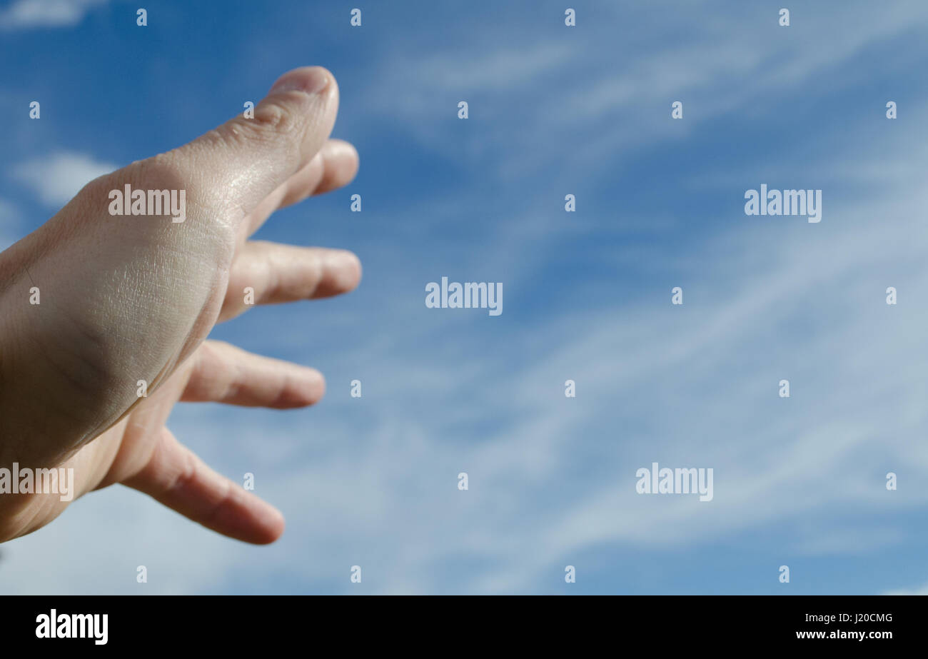 Hand stretching out against blue sky Stock Photo - Alamy
