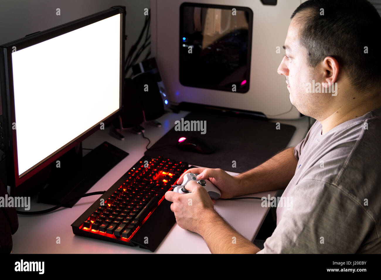 Man playing computer game on custom made desktop with joypad, keyboard ...