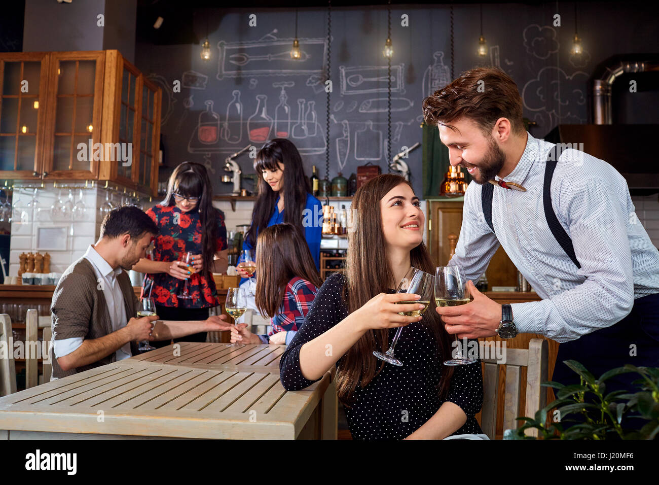 Meeting friends at the bar restaurant. A couple of men and girl chat in ...