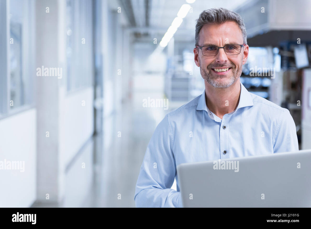 Manager on shop floor of factory using laptop Stock Photo - Alamy