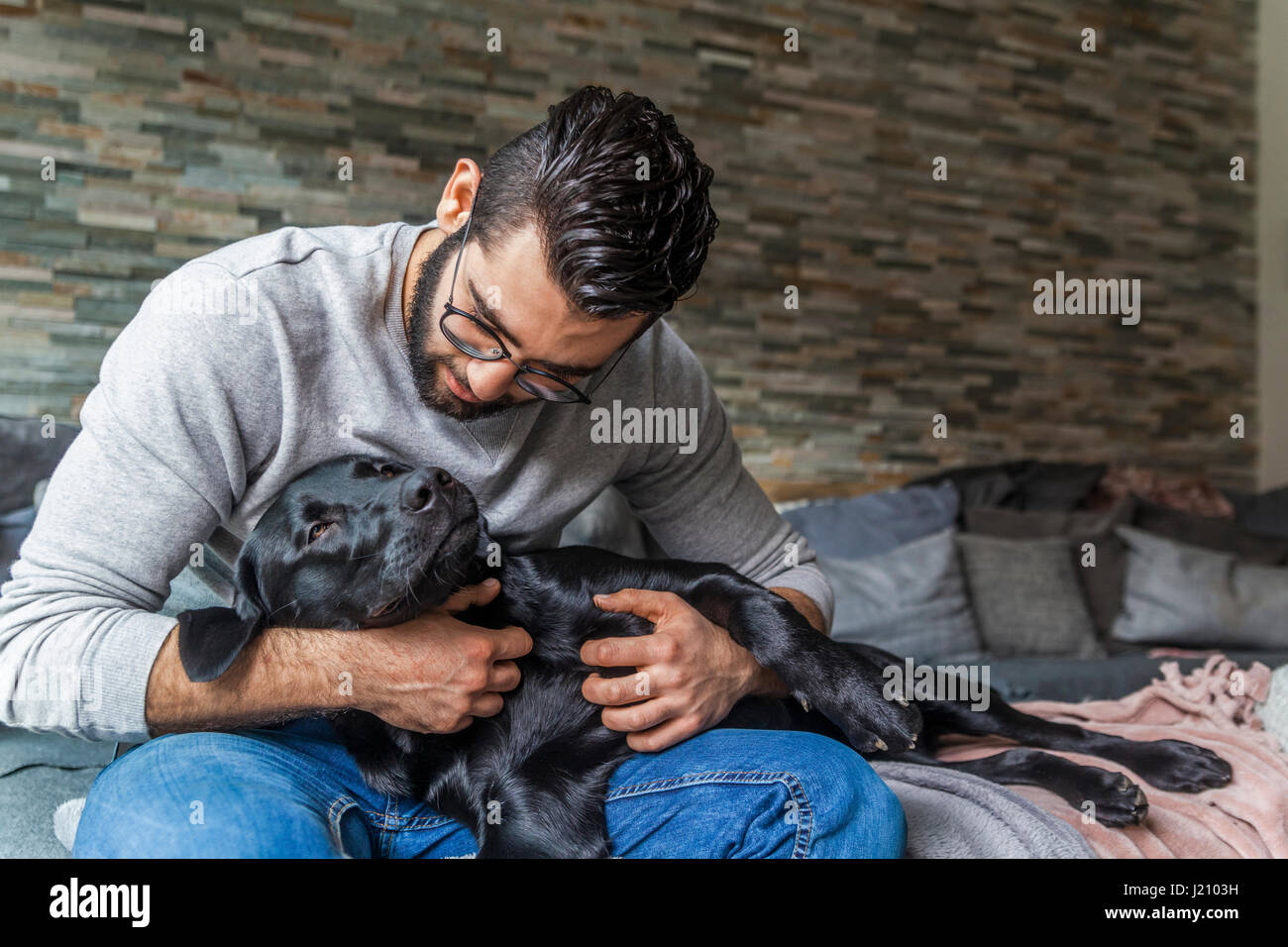 Man cuddling with his dog on the couch at home Stock Photo - Alamy