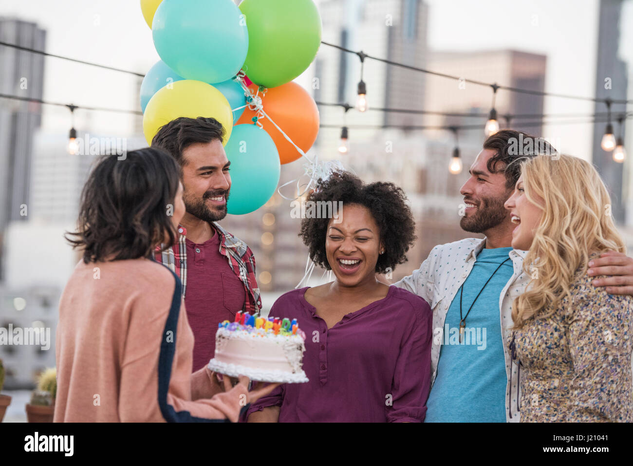 Friends celebrating birthday party on rooftop with birthday cake Stock ...
