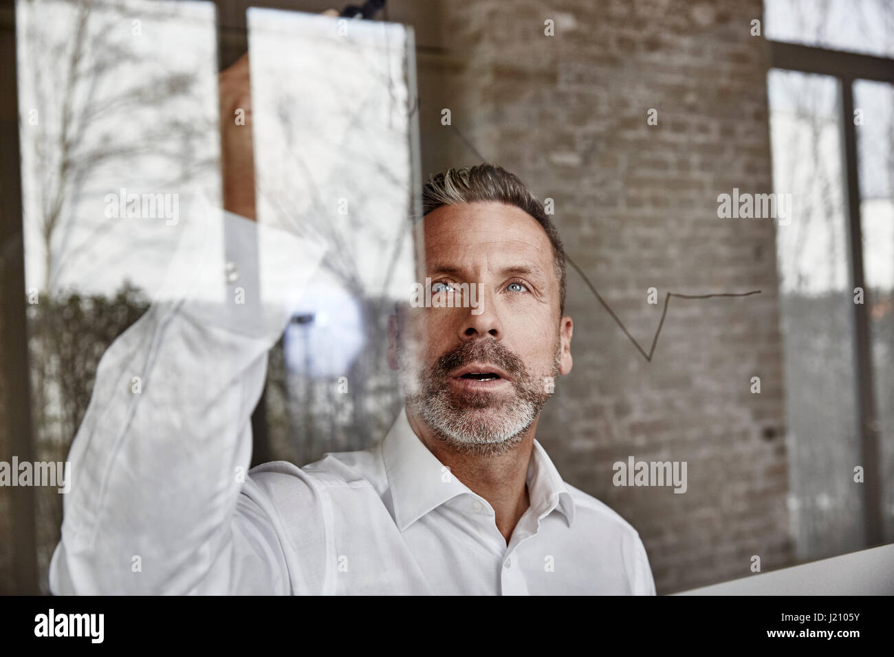 Businessman drawing on glass pane Stock Photo - Alamy