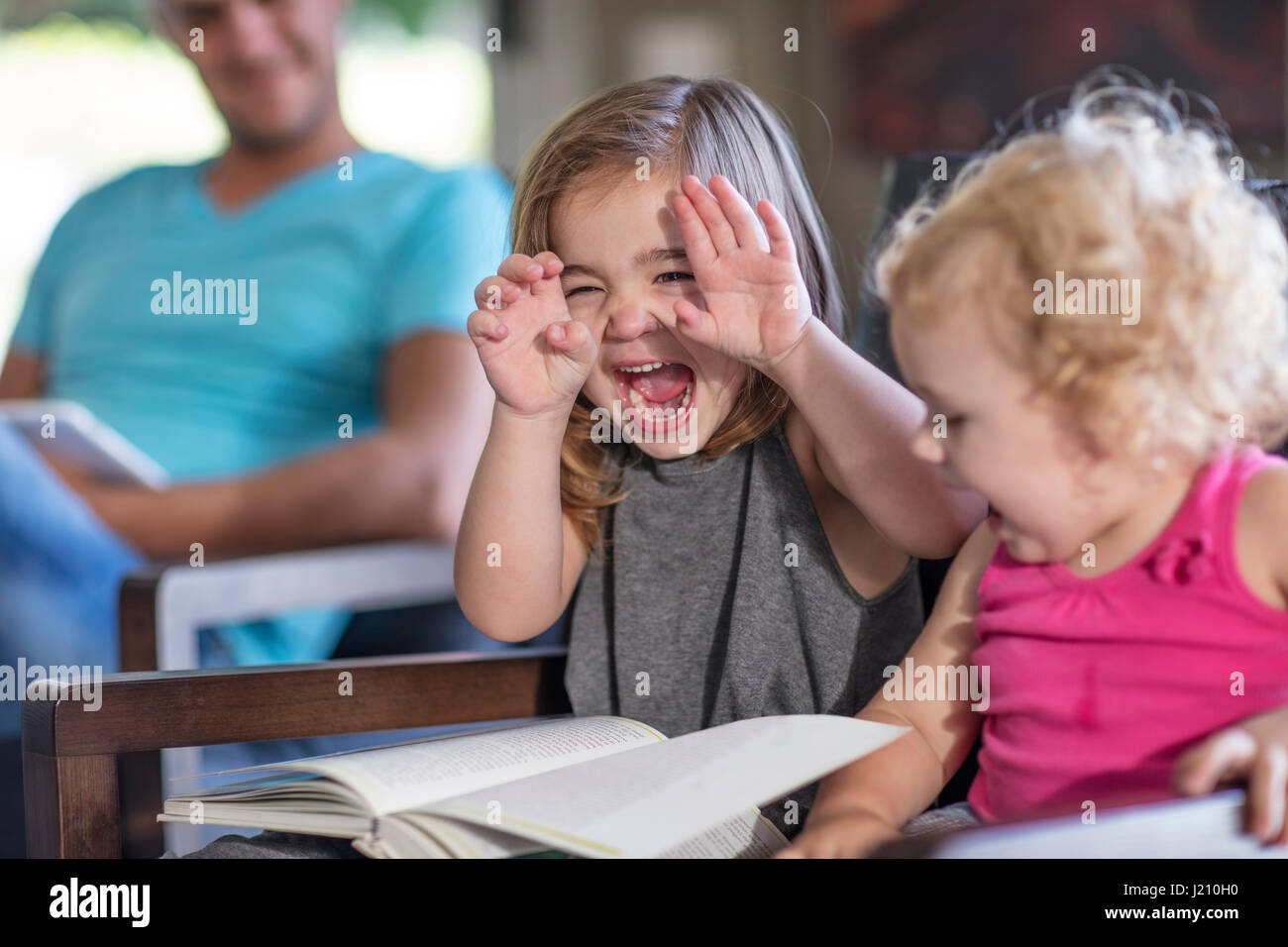 Two little girls reading book and having fun Stock Photo - Alamy