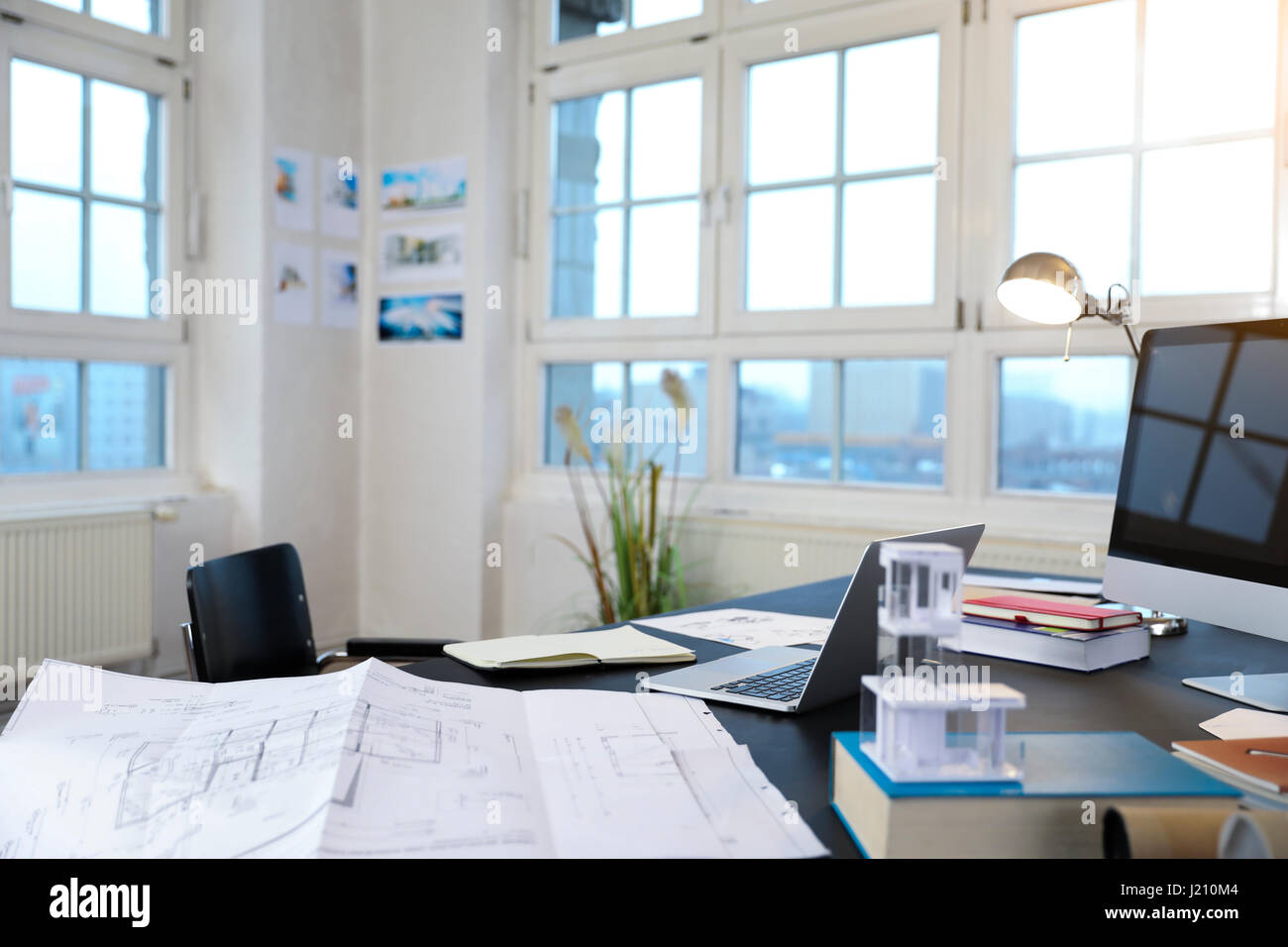 Desk with construction plan in a modern informal office Stock Photo - Alamy