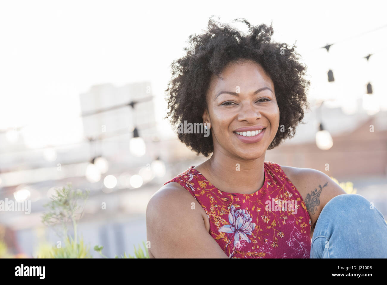 Young woman sitting on rooftop terrace, enjoying the sun Stock Photo ...