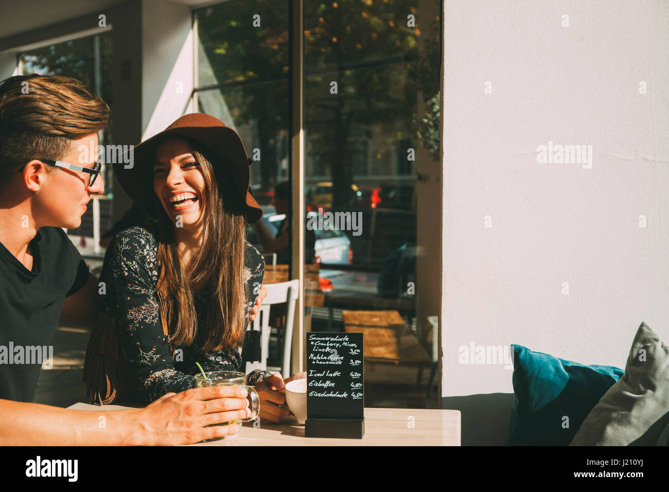 Couple sitting in a coffee shop having fun Stock Photo - Alamy