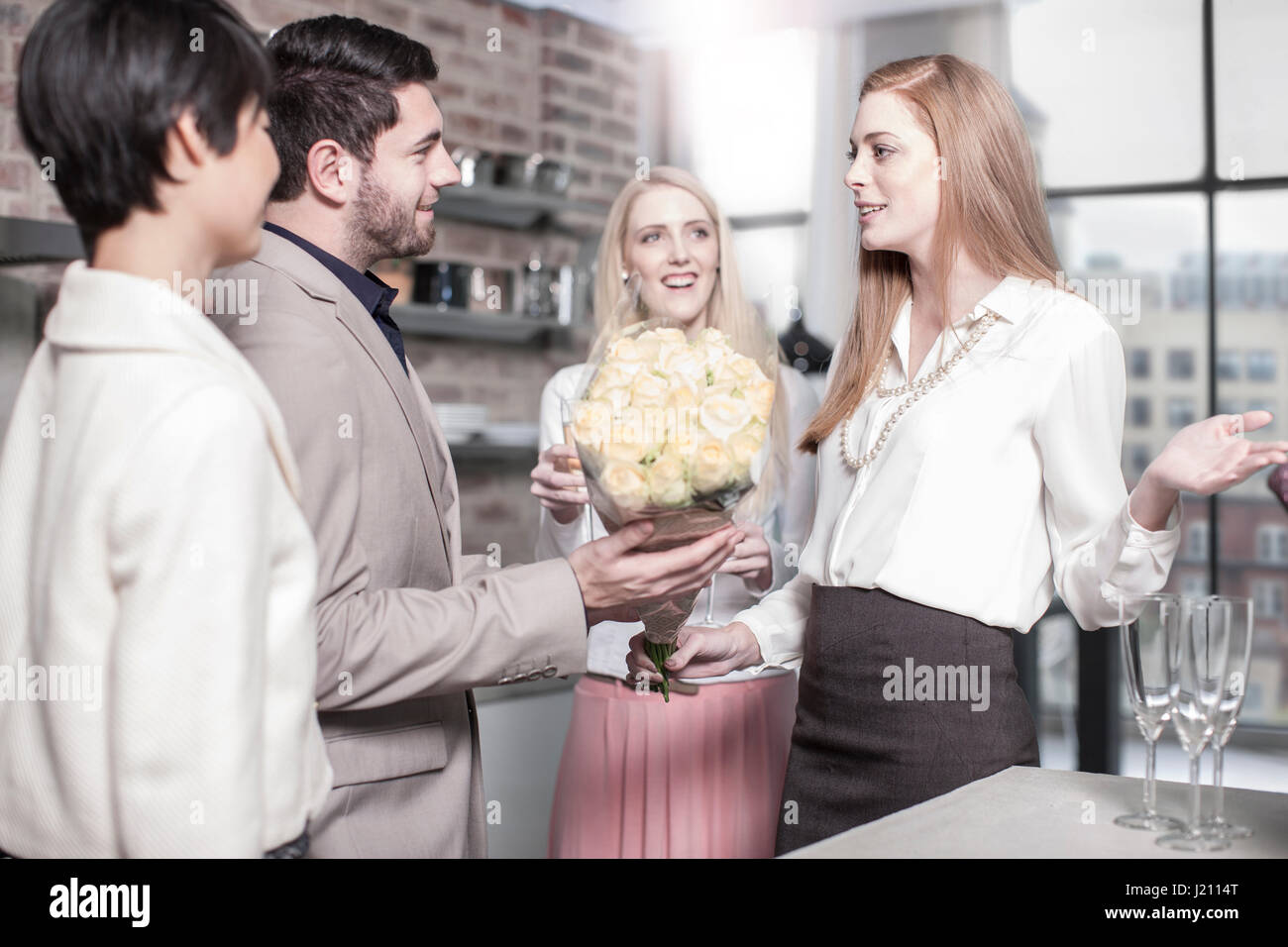 Man handing over roses to woman in kitchen Stock Photo - Alamy
