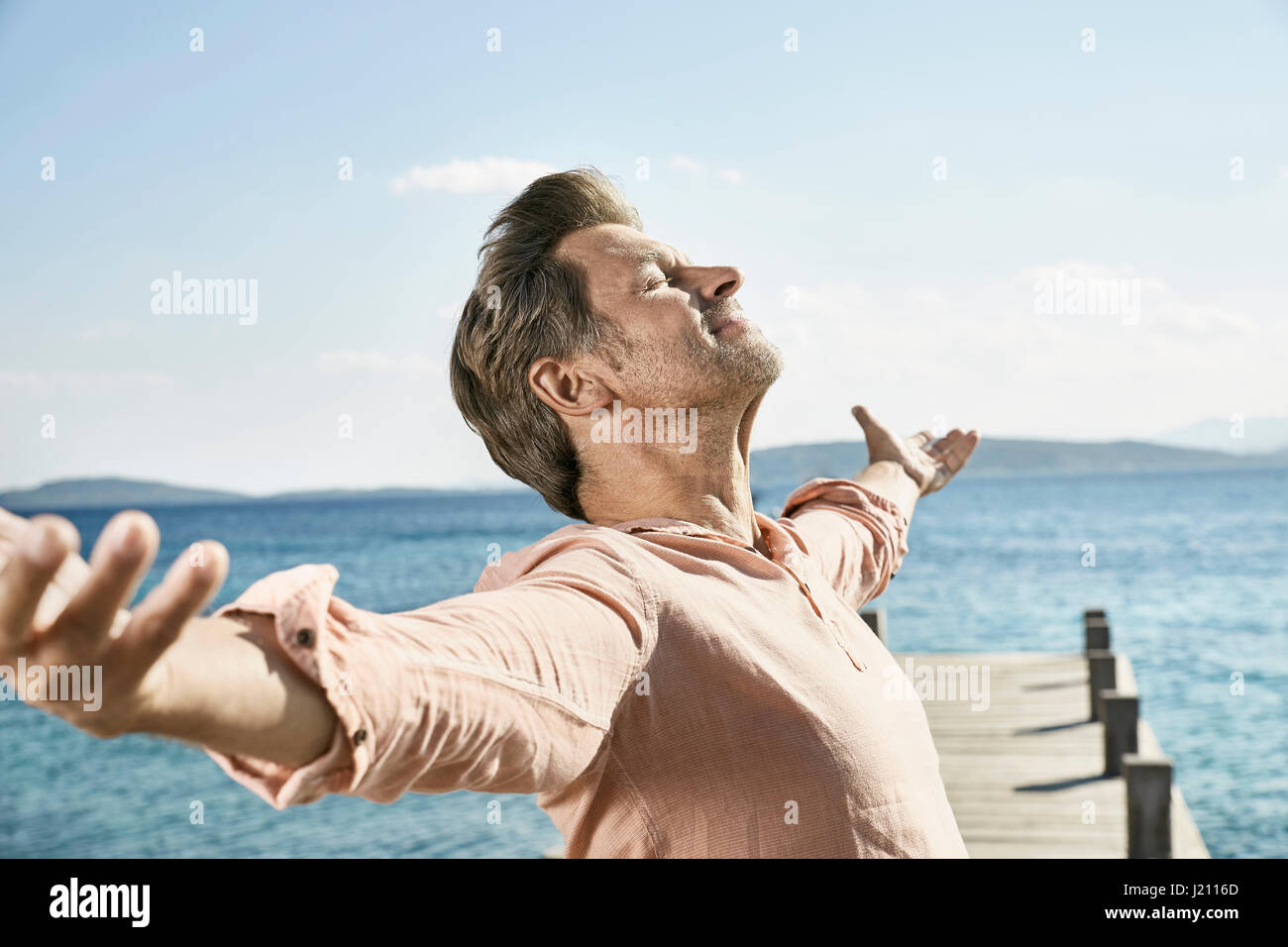 Man on jetty enjoying sunlight Stock Photo - Alamy