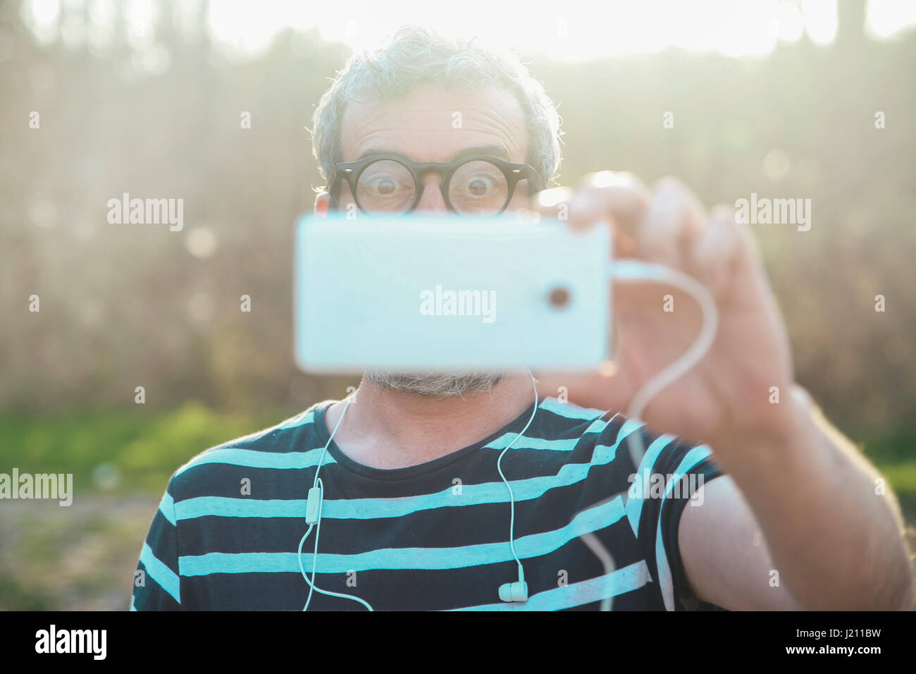 Starring man taking picture of viewer with smartphone Stock Photo - Alamy