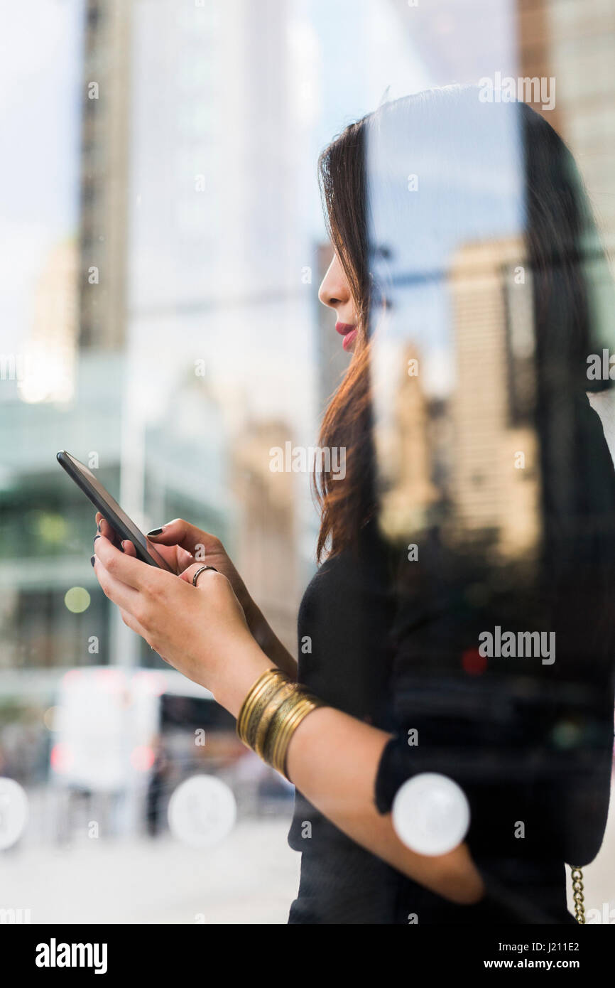 USA, New York City, Manhattan, young woman behind glass pane looking at ...