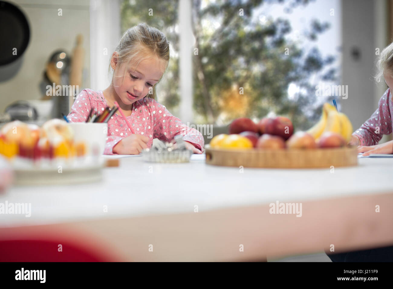Two girls doing homework in kitchen Stock Photo - Alamy